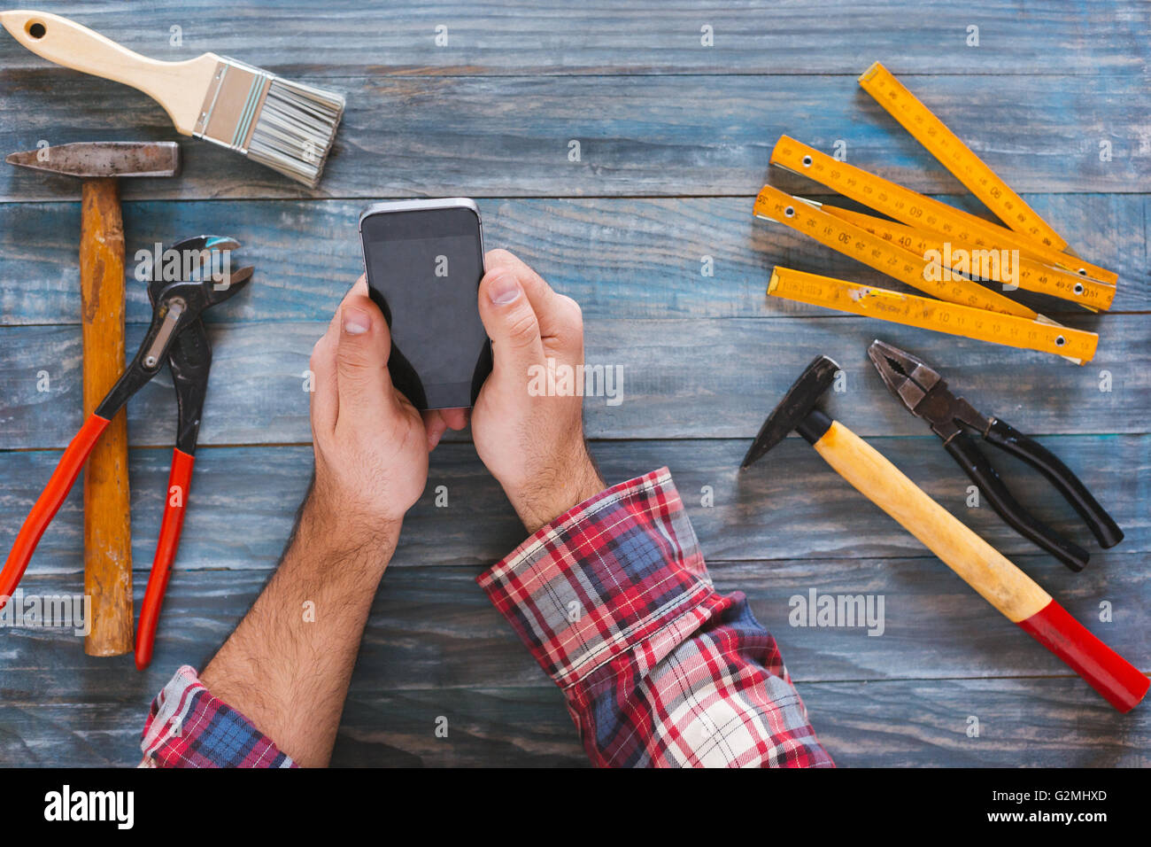 Man working on a DIY project with his phone, wood shavings and ...