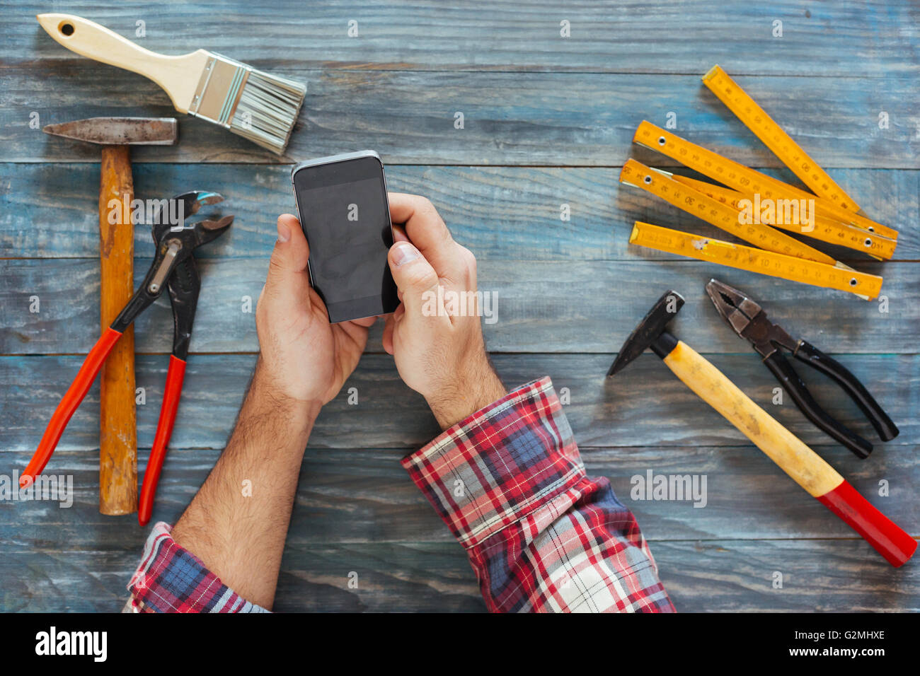 Man working on a DIY project with his phone, wood shavings and ...