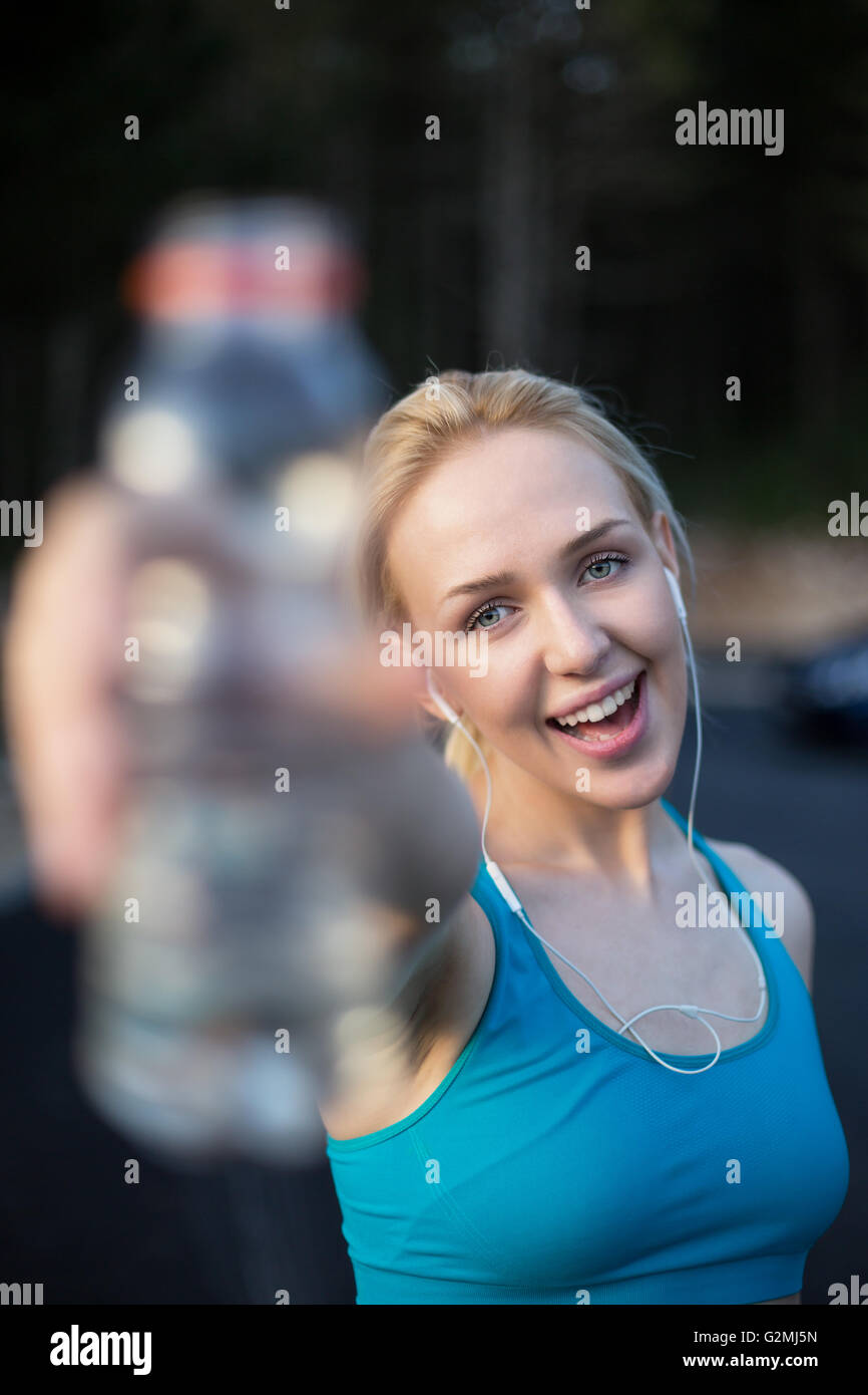 Beautiful young runner holding a bottle of water at a running track ...