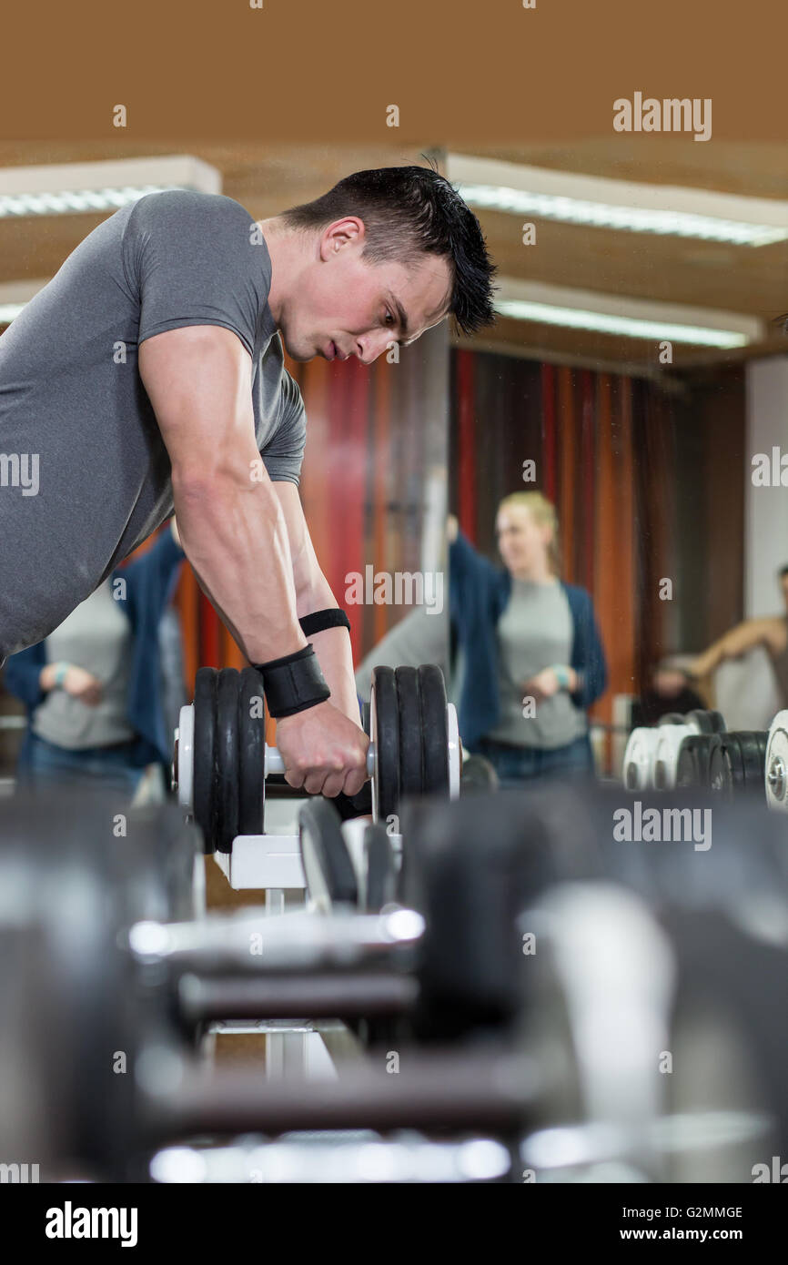 Handsome man lifting dumbbell at gym Stock Photo - Alamy