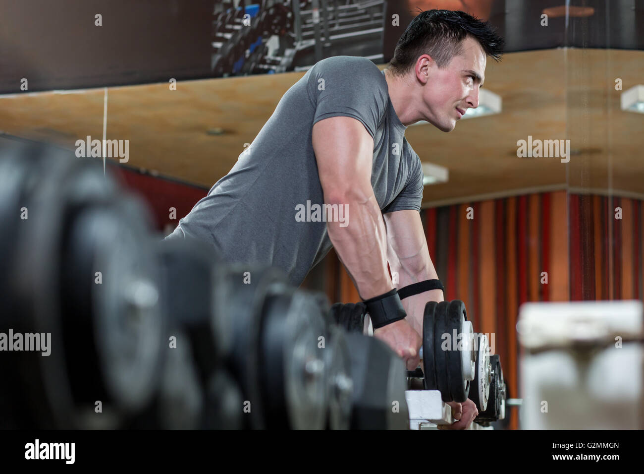 Handsome man lifting dumbbell at gym Stock Photo - Alamy