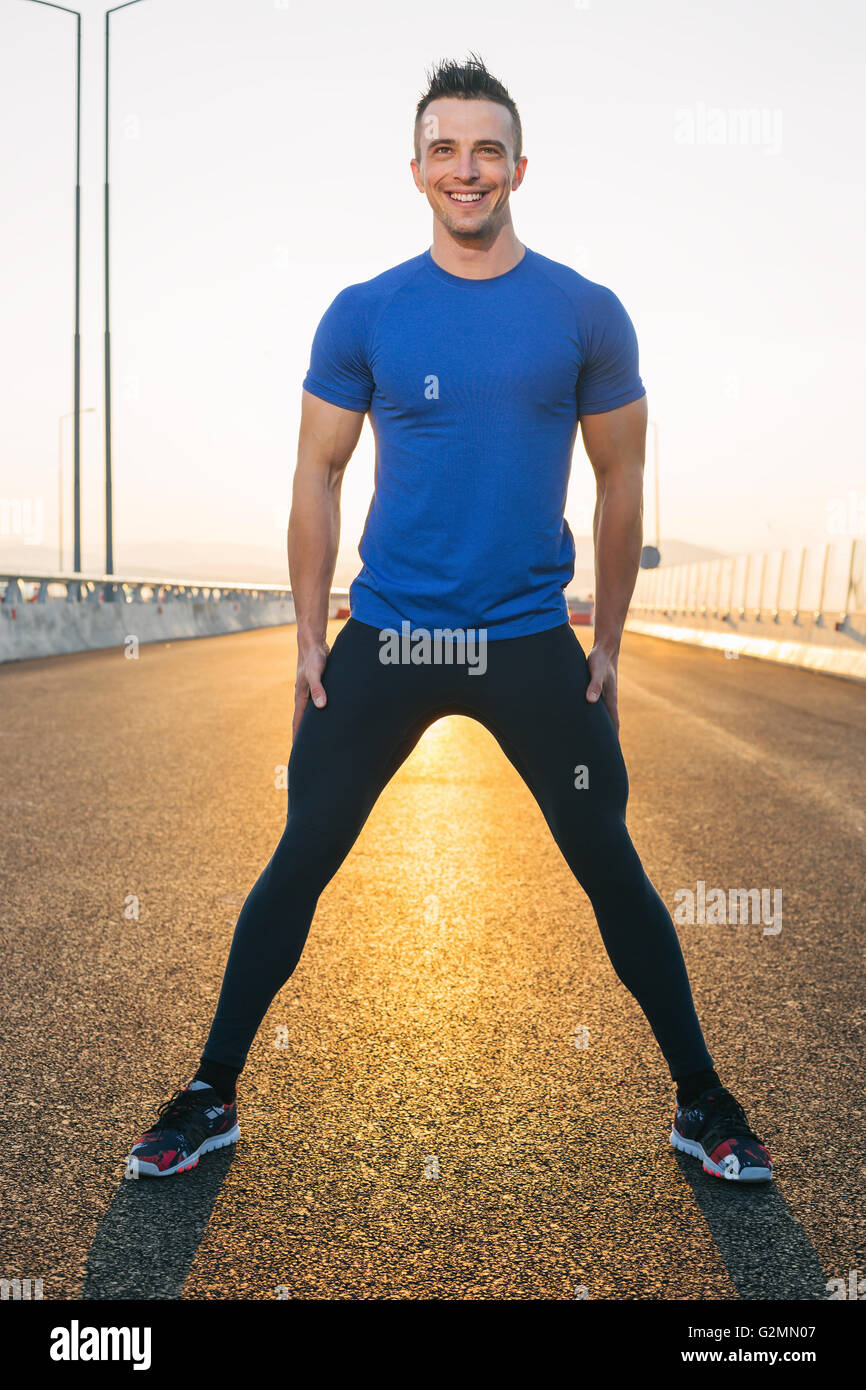 Portrait Of Male Runner On highway sunset, streching legs Stock Photo ...
