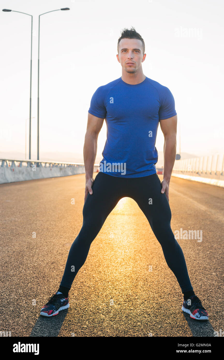 Portrait Of Male Runner On highway sunset, streching legs Stock Photo ...