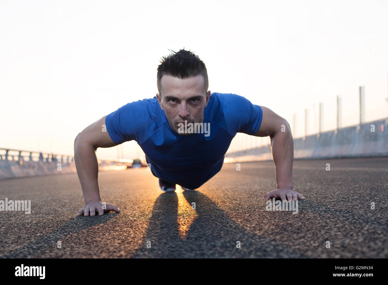 Handsome male runner doing push-ups on stairs in urban setting, young ...