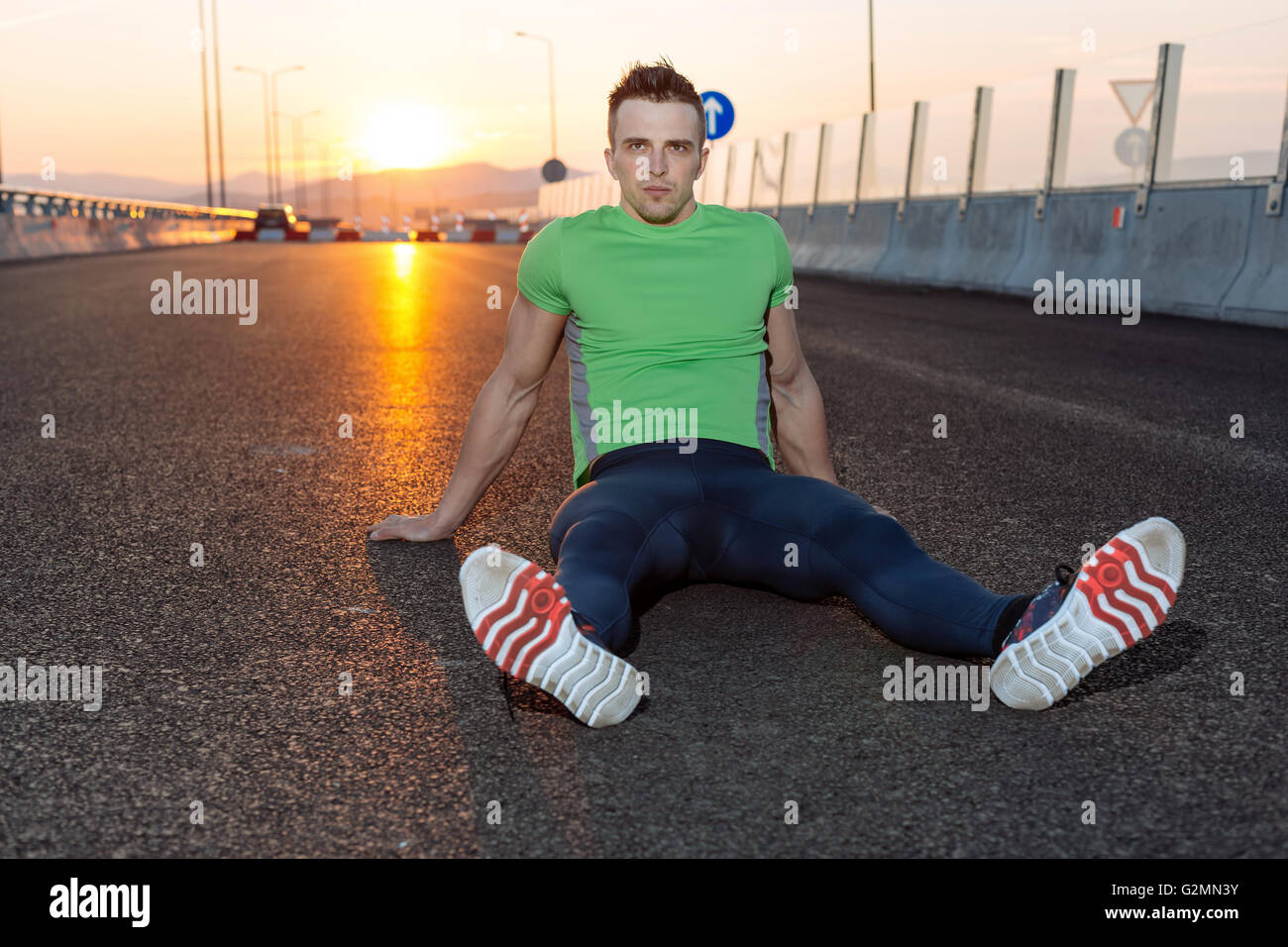 runner resting lying on a black asphalt after running. Jogging man ...