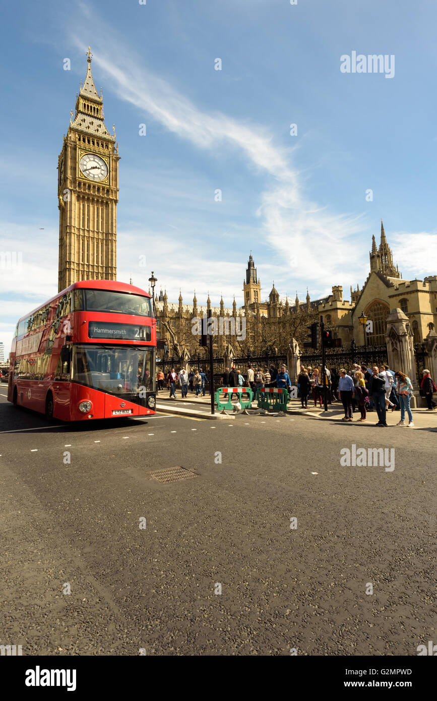 Modern red bus travels past Big Ben, Parliament Square in London during ...