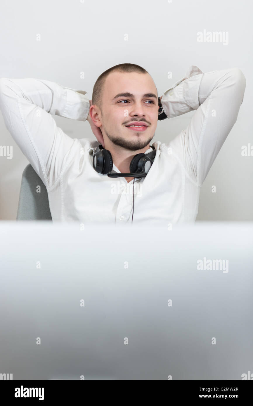 Contented businessman taking a break sitting back in his chair at the ...