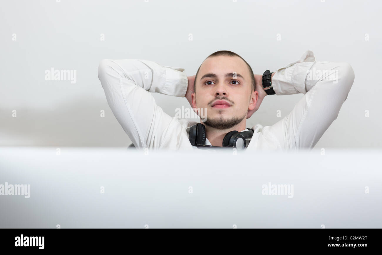 Contented businessman taking a break sitting back in his chair at the ...