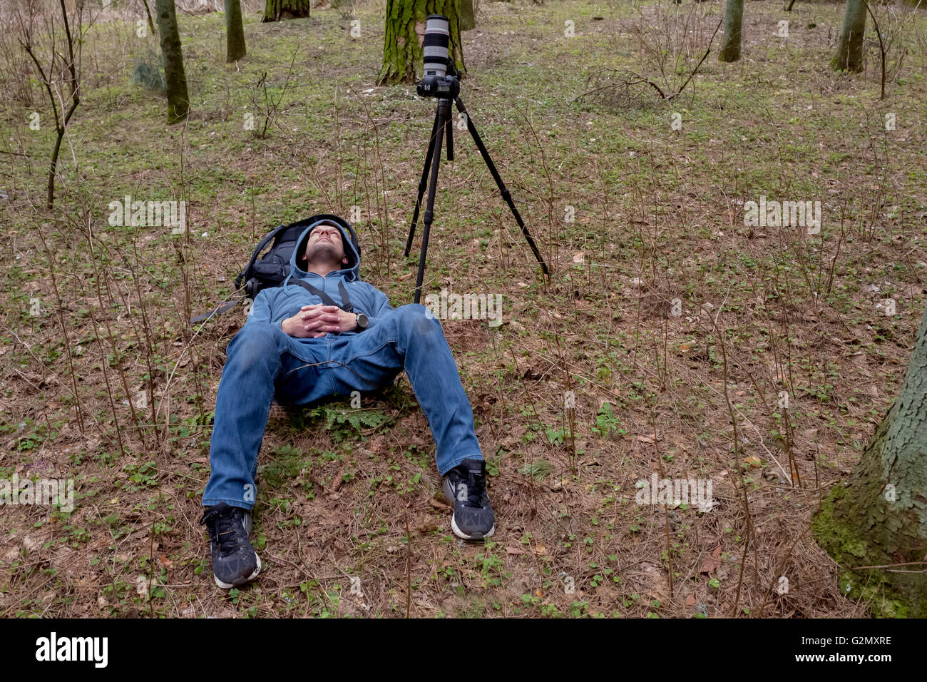 Photographer is laying on the ground near of the standing camera and ...