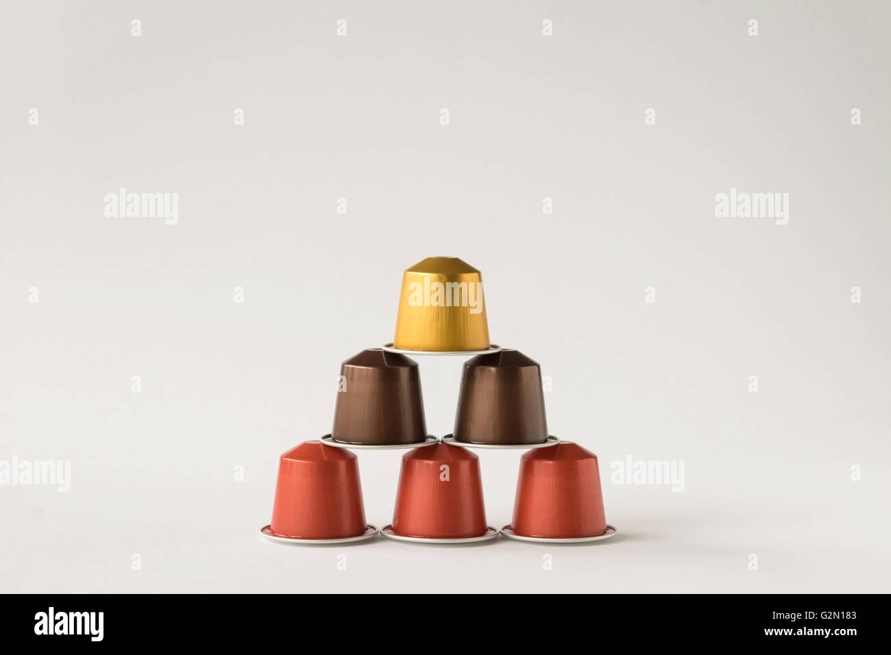Pyramid of metallic look pods for coffee machine on plain white ...