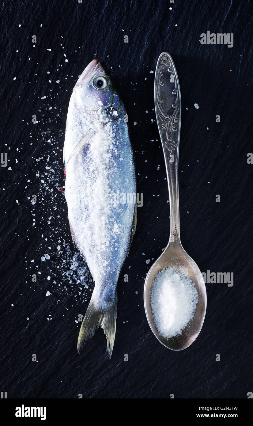 raw fish and salt on the black board Stock Photo - Alamy