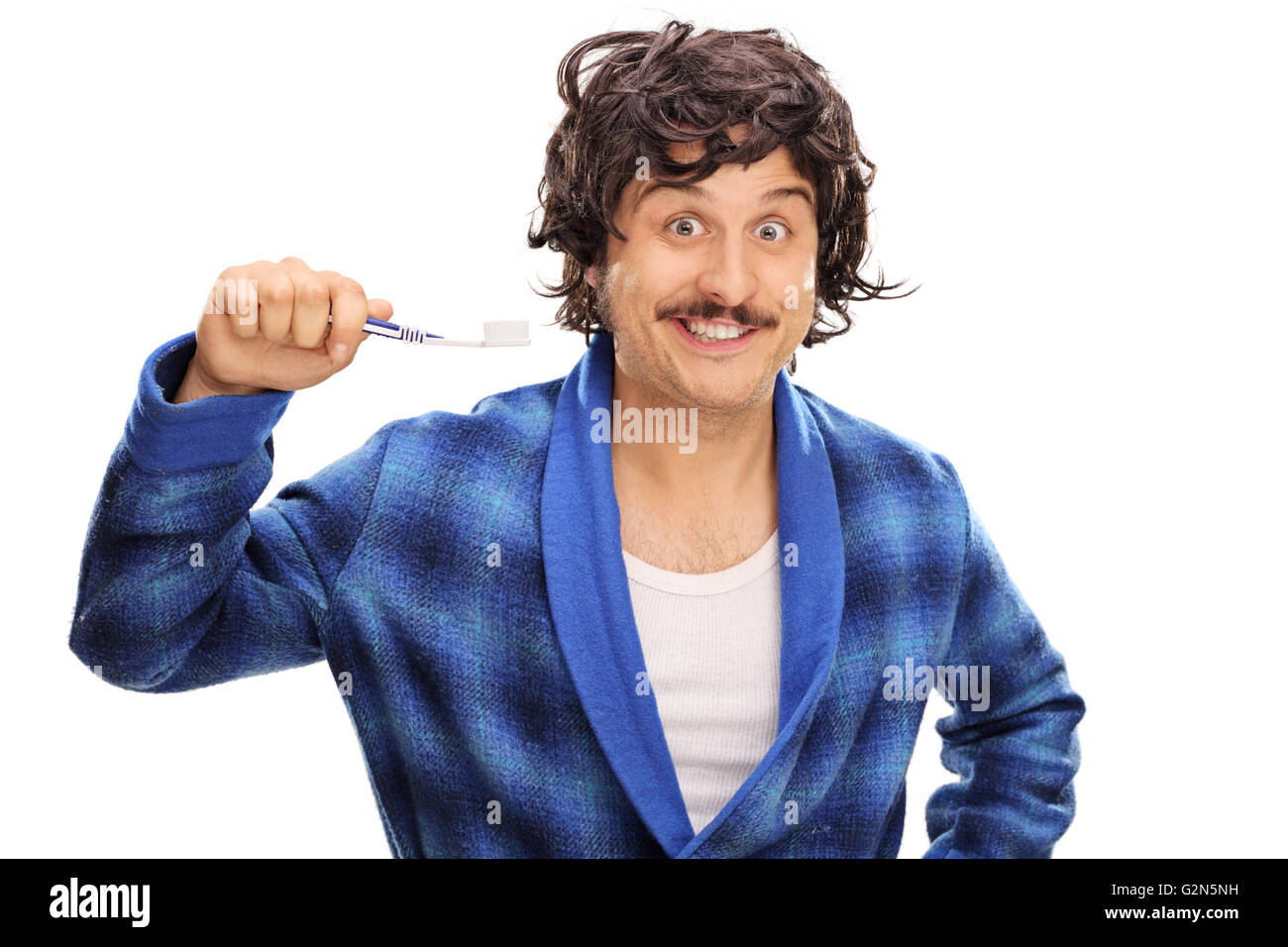 Young joyful man in a blue bathrobe holding a toothbrush isolated on white background Stock ...