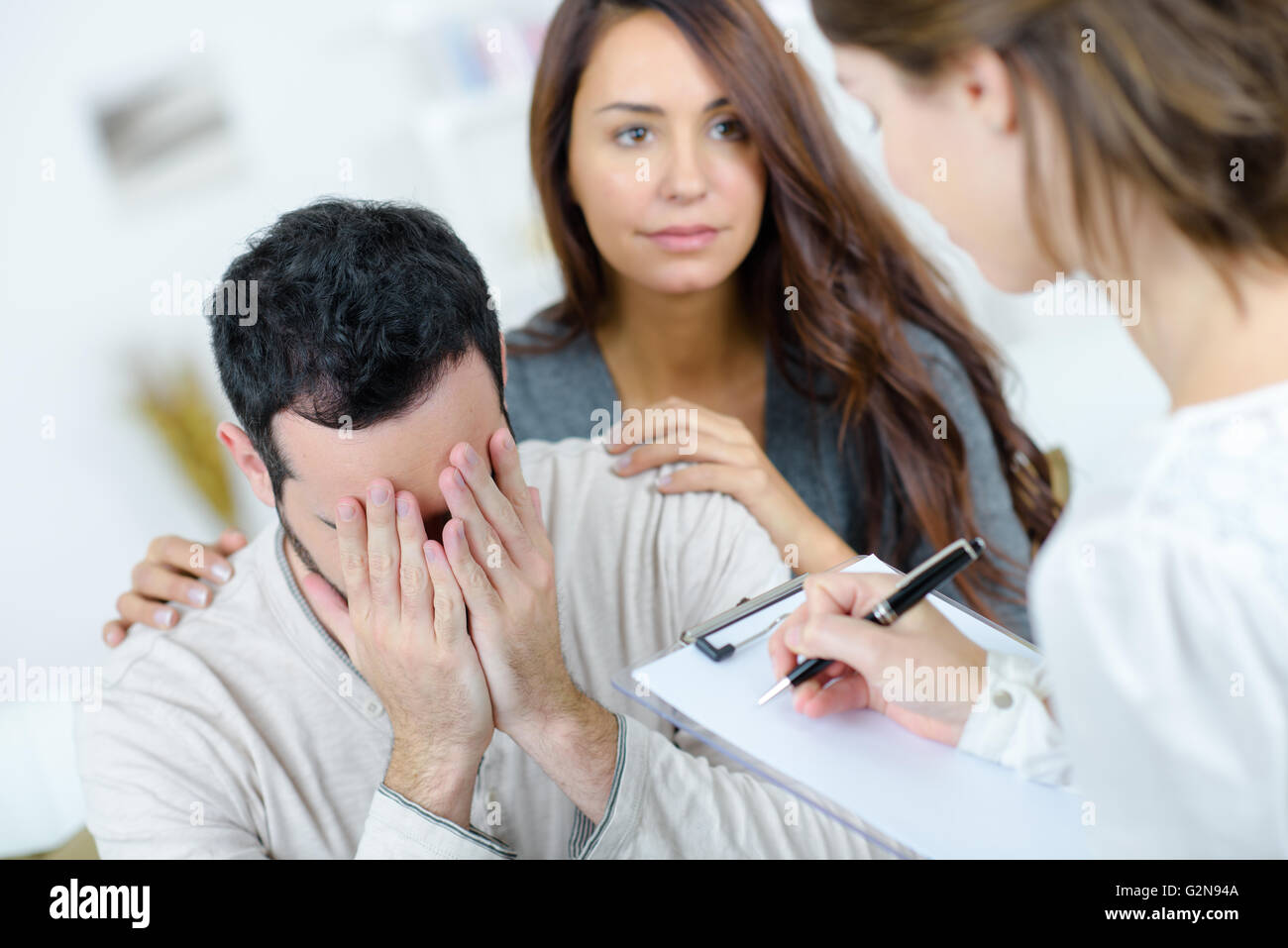Lady comforting distressed man, woman with clipboard Stock Photo - Alamy
