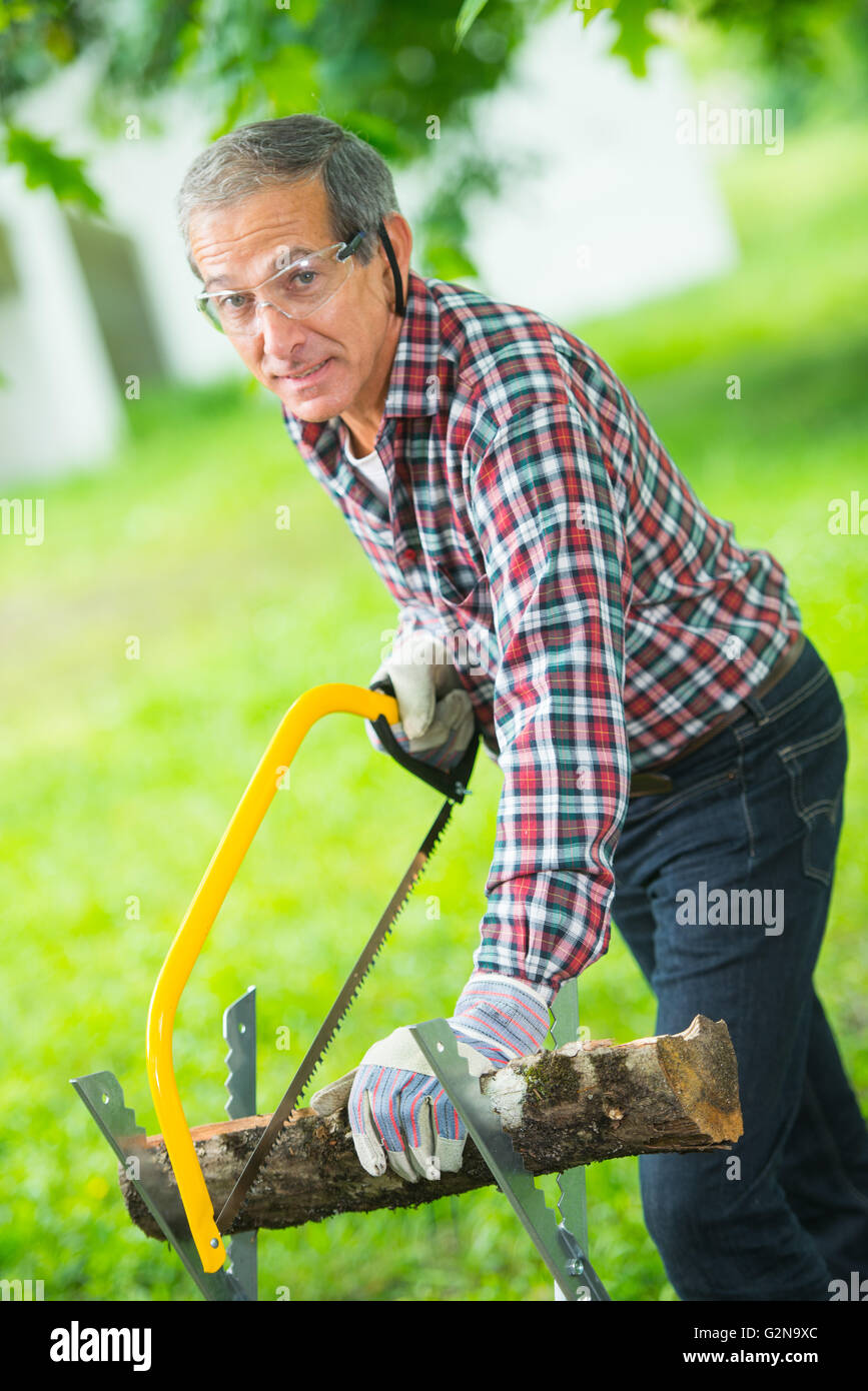 Senior man sawing a log handsaw closeup Stock Photo - Alamy