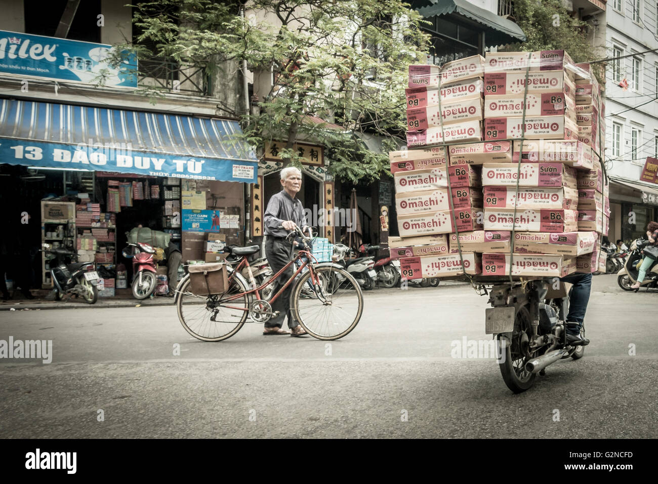Vietnamese person pushing a traditional bike alongside a heavily ...