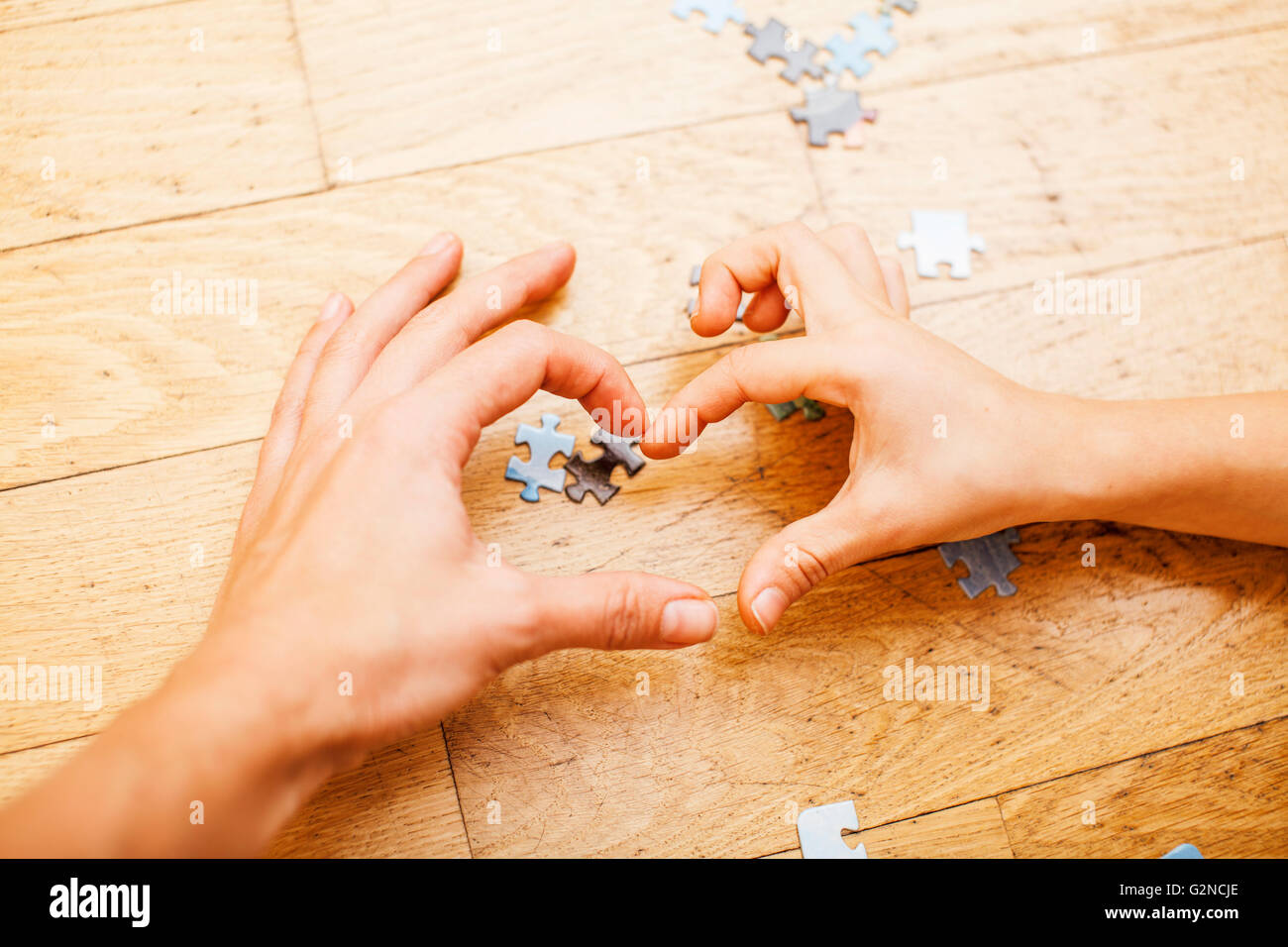 little kid playing with puzzles on wooden floor together with parent ...