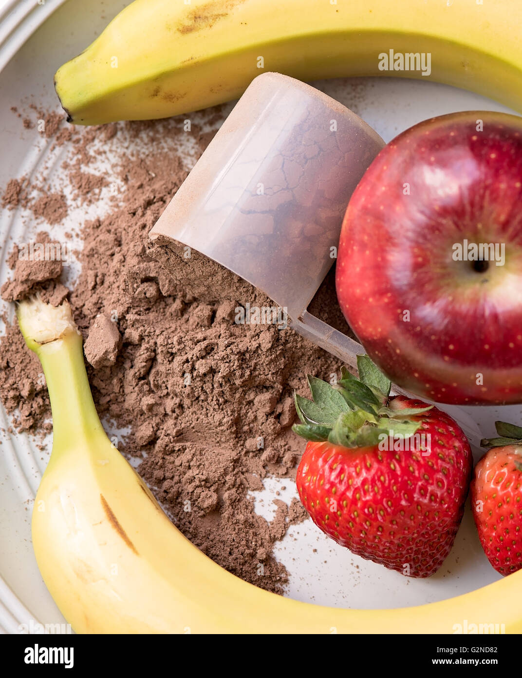 Chocolate shake powder on a plate with apples, bananas and strawberries ...