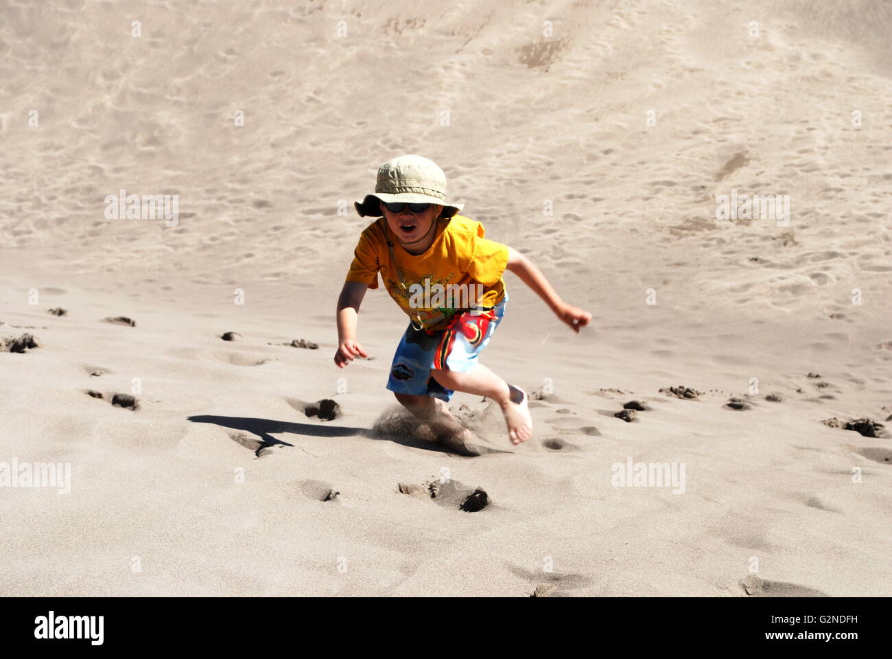 A young boy running up a sand dune Stock Photo - Alamy