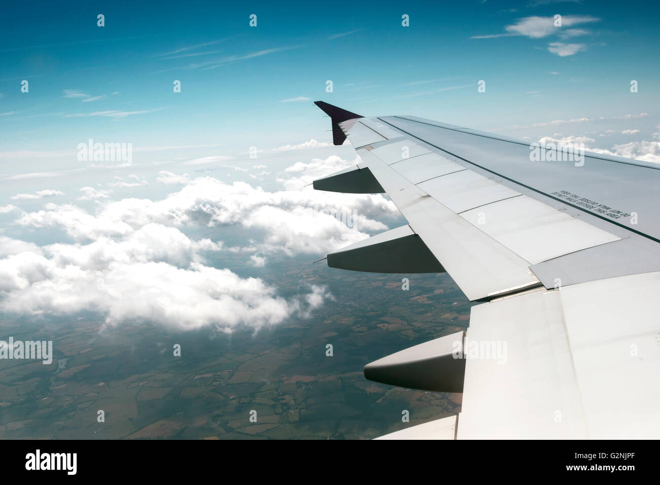 Airplane window view with the wing and the earth, blue sky an clouds ...