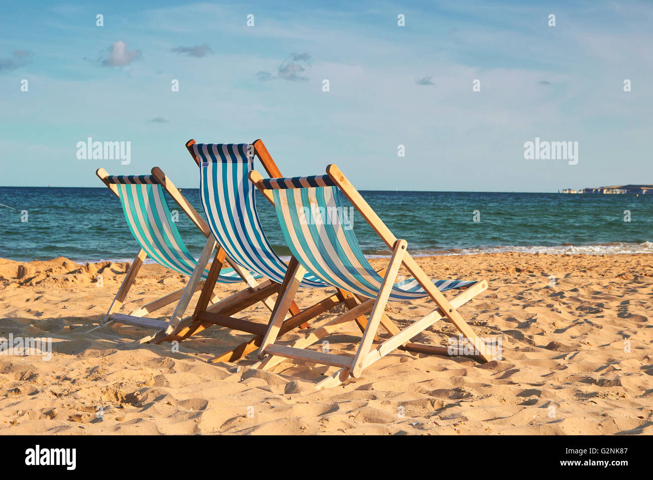 Three beach chairs on a golden beach with blue sky, cinematic view ...