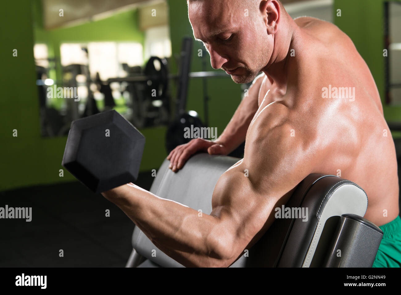 Young Man Working Out Biceps In Gym - Dumbbell Concentration Curls ...