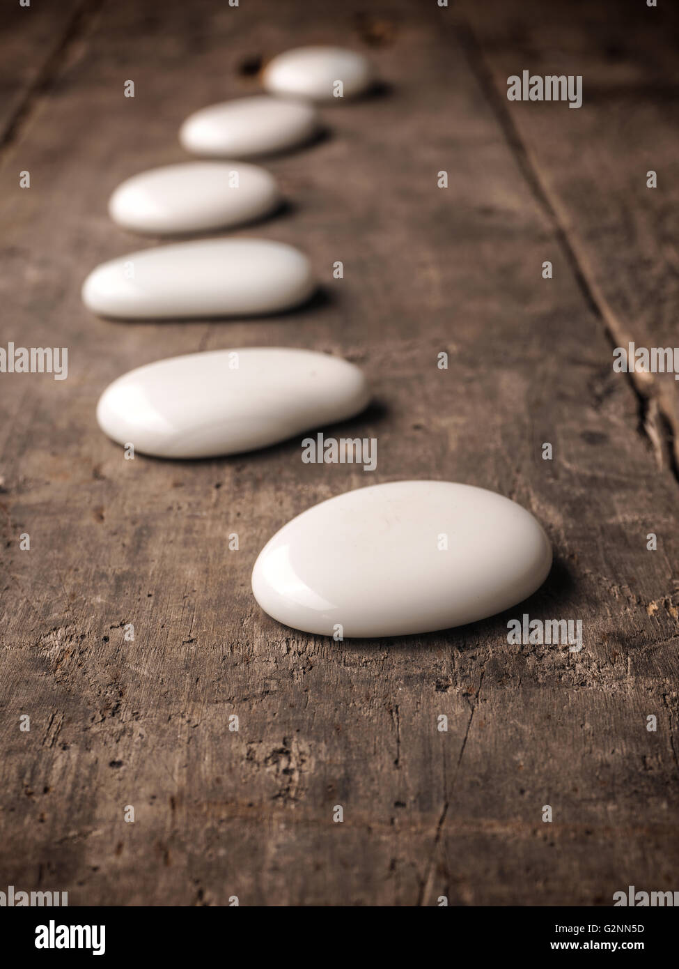White stones in a row on an old rustic wooden table Stock Photo - Alamy