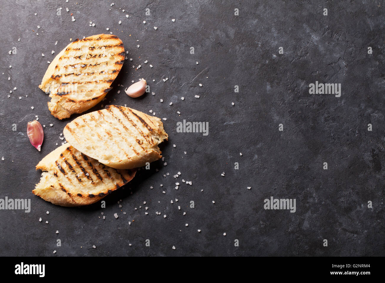 Toast bread with salt and garlic on stone table. Top view with copy ...