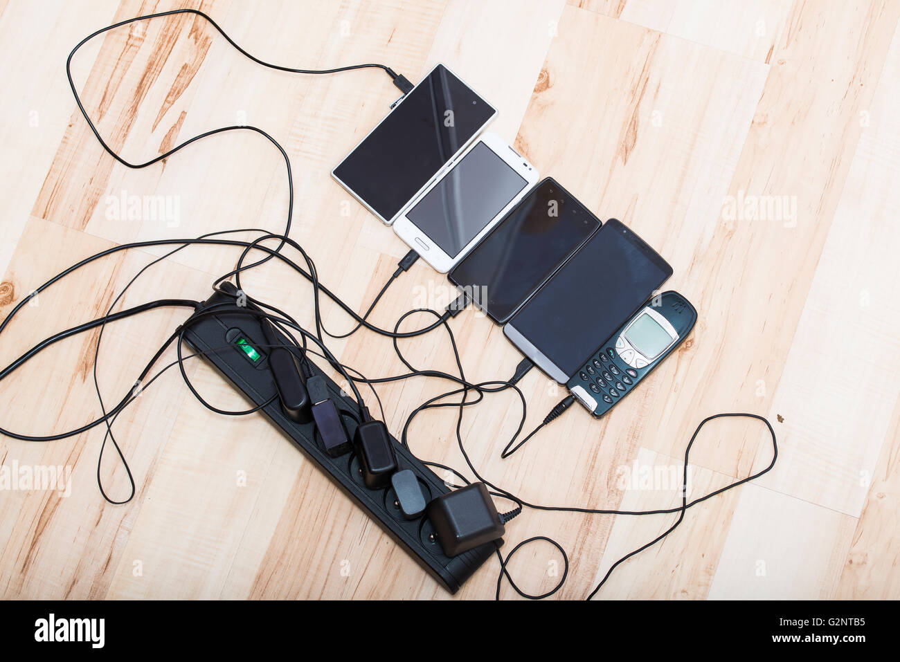 four smartphones and one classic phone connected to chargers Stock ...