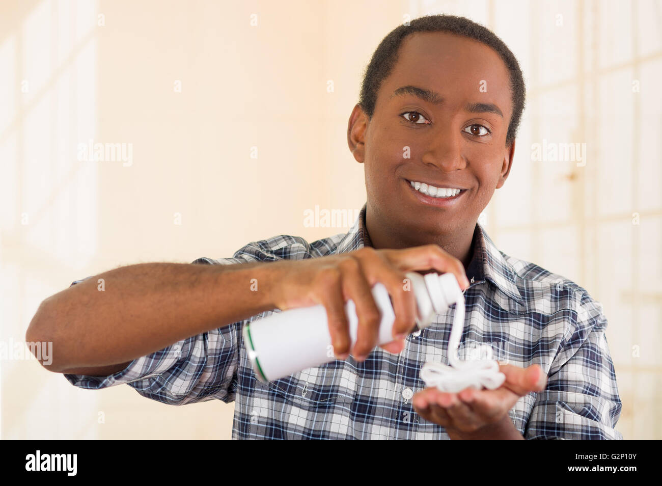 Handsome young man wearing white blue square pattern shirt squeezing ...