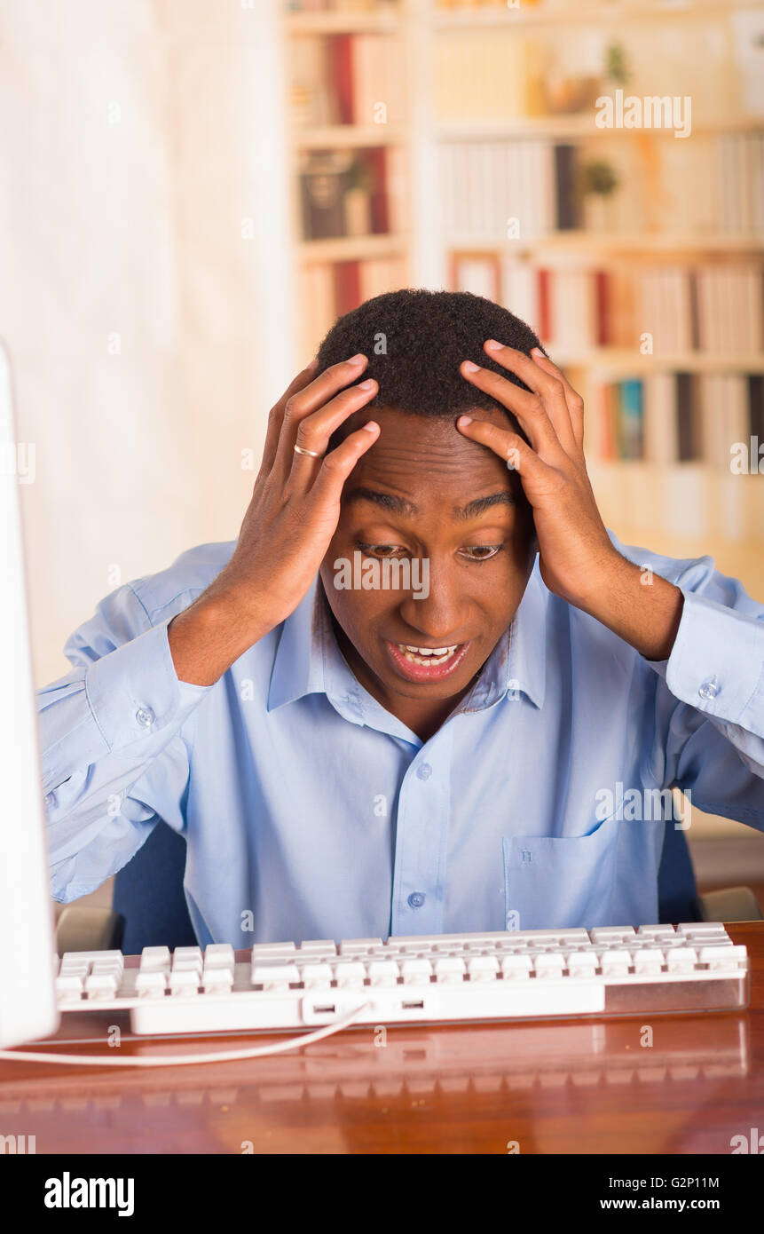 Young handsome man wearing blue office shirt sitting by computer ...