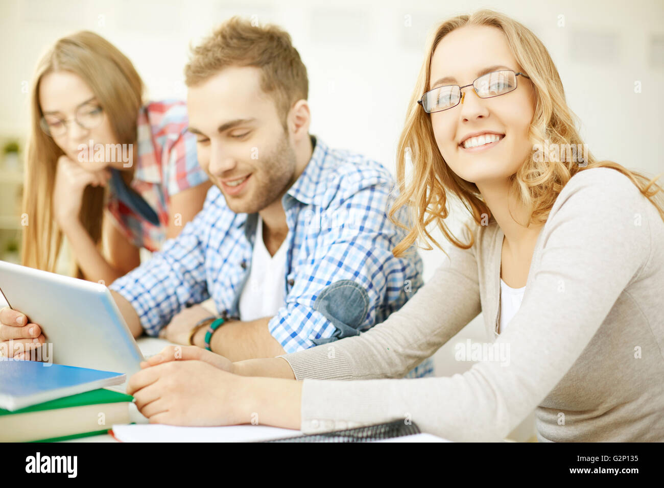 Happy teenage student looking at camera on background of her group ...