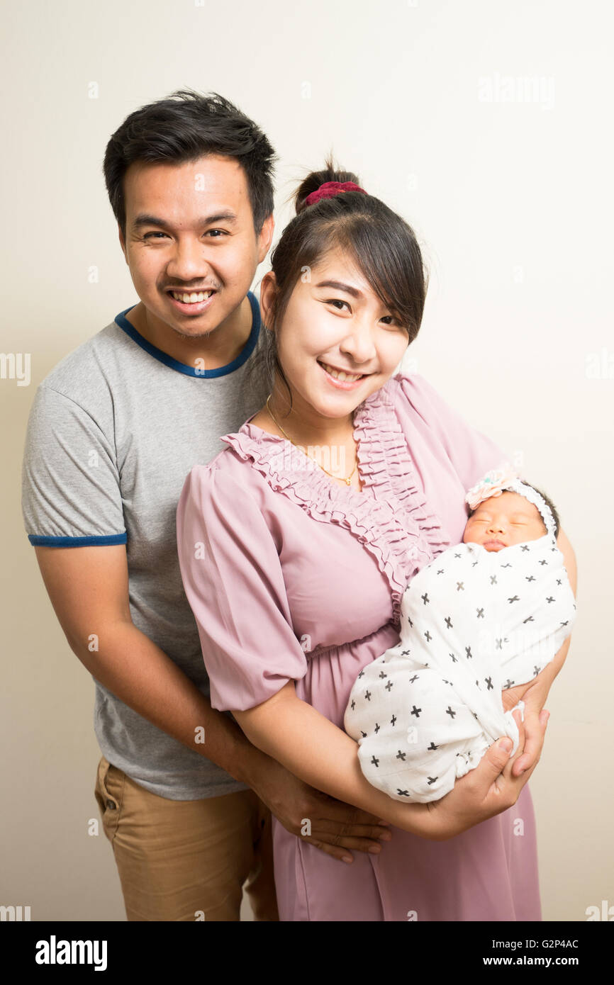 Portrait of Asian parents and six months old baby girl at home. Asian ...