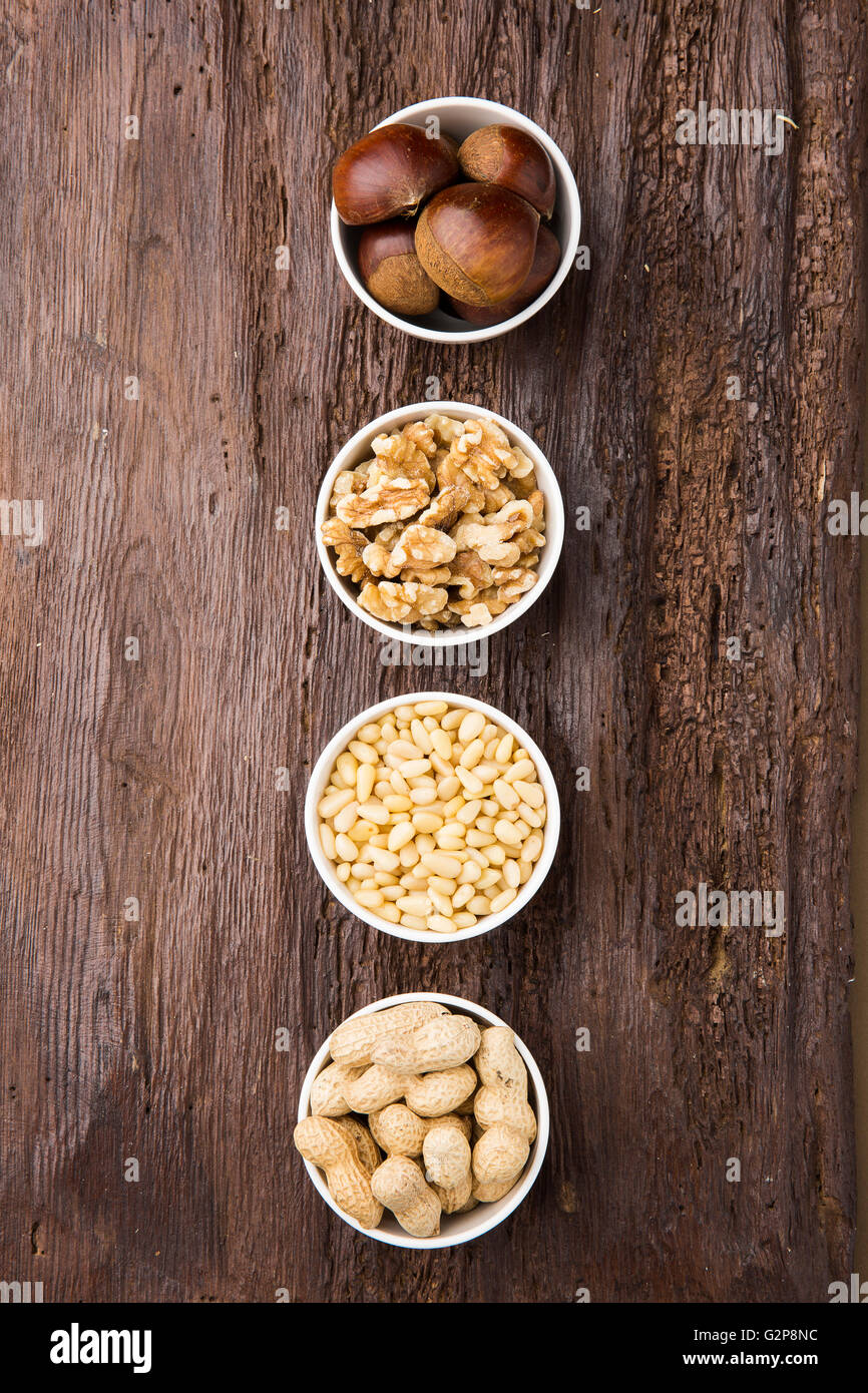 Different types of nuts in white bowls from high angle view with wooden ...