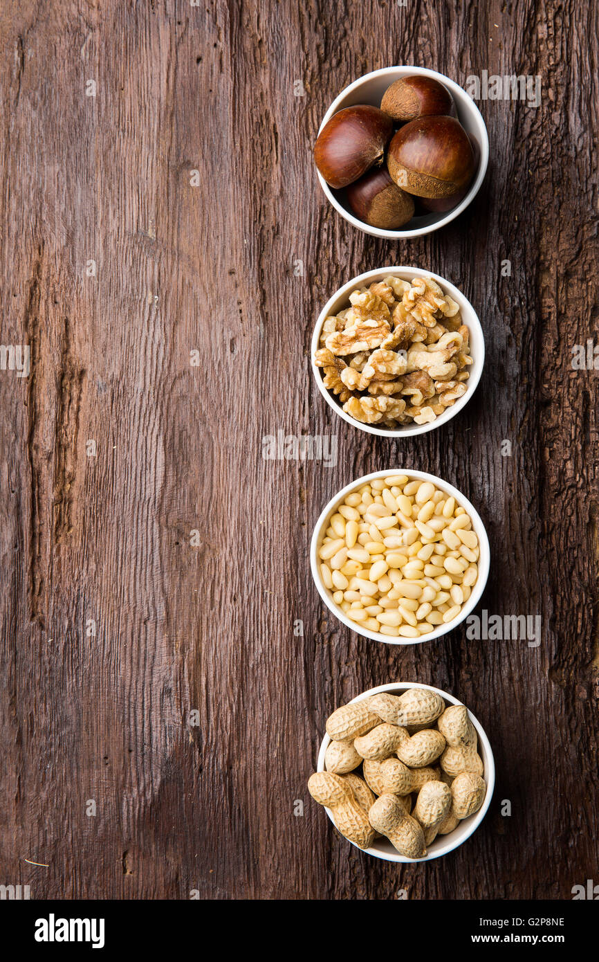 Various types of nuts in white bowls from high angle view with wooden ...