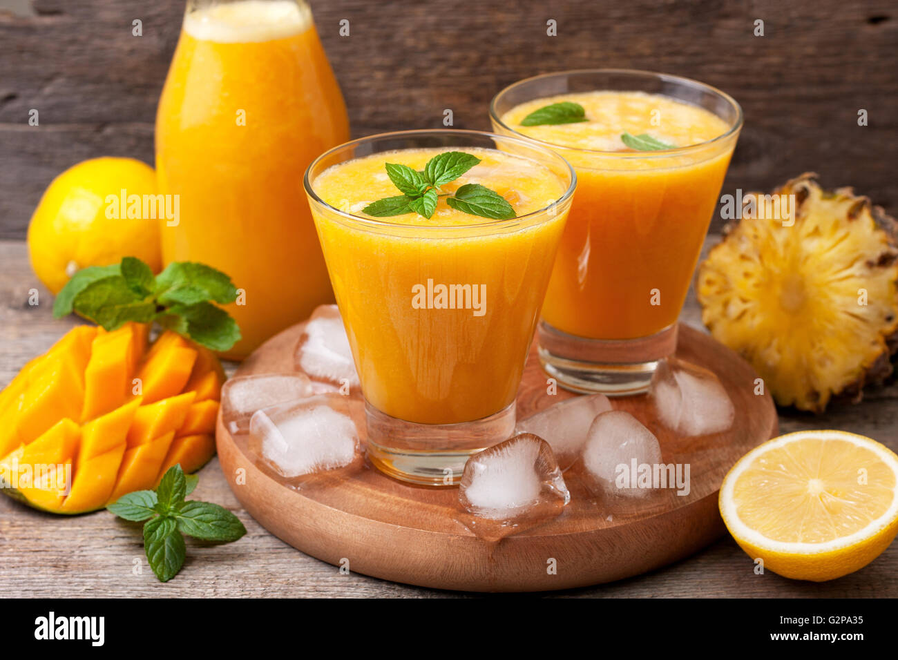 Tropical lemonade with mango, pineapple and mint in glasses and bottle ...