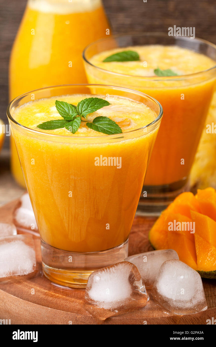 Tropical lemonade with mango, pineapple and mint in glasses and bottle ...