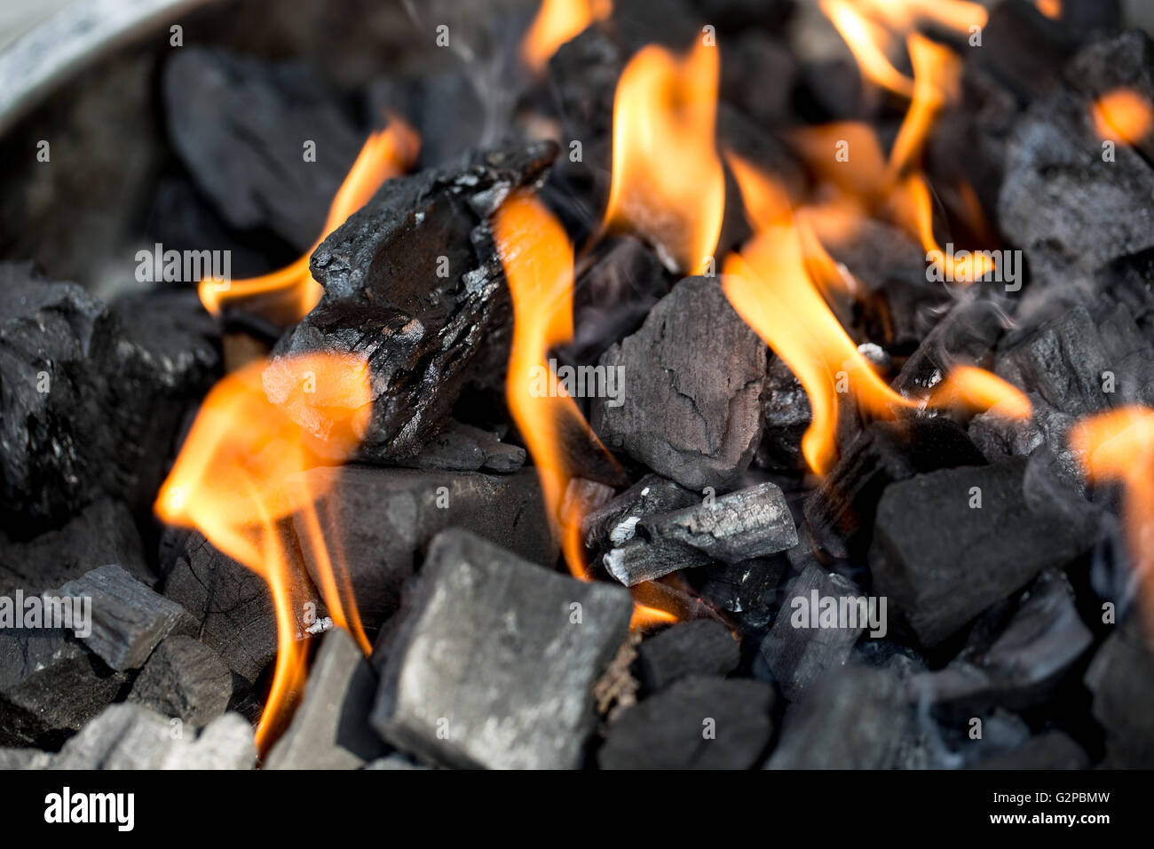 Igniting charcoal for a barbecue with bright orange flames Stock Photo ...