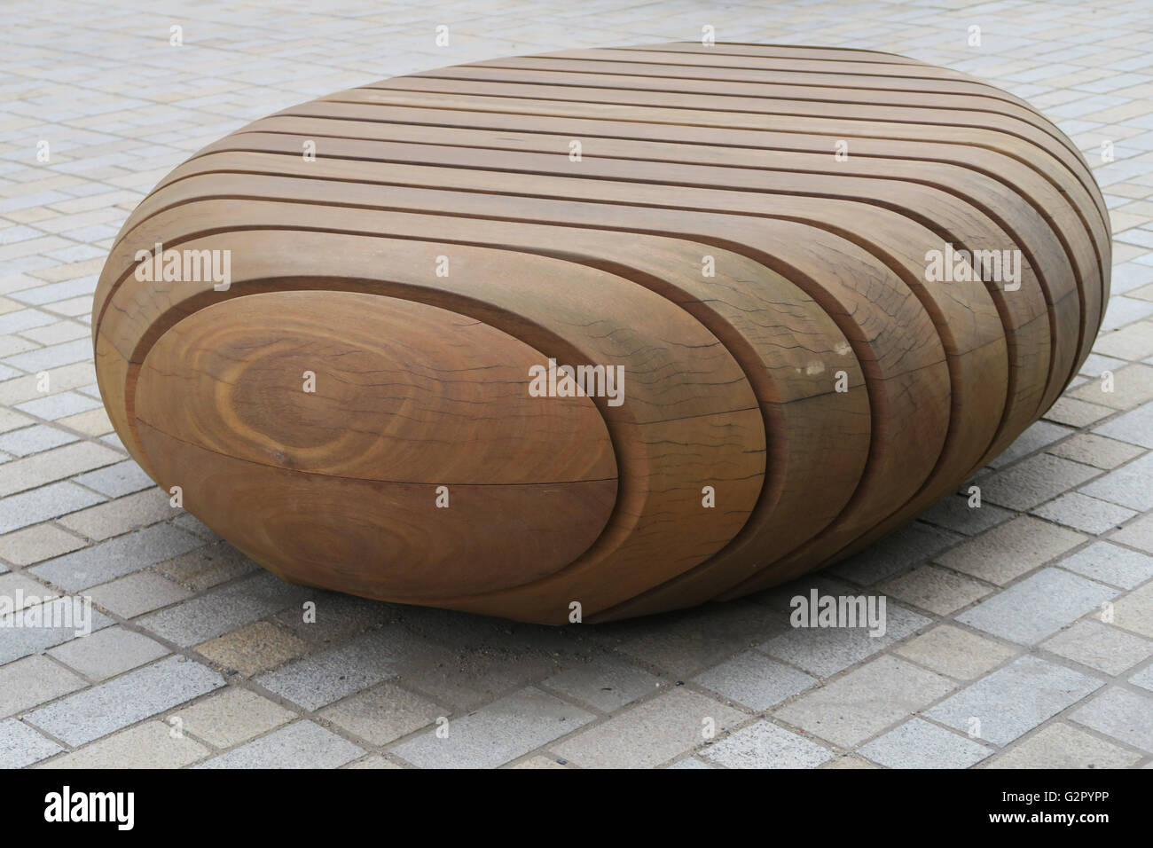 Wooden oval shape bench art against brick pavement Stock Photo - Alamy