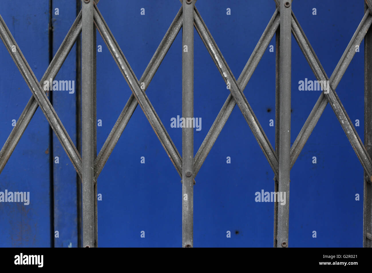 Concertina metal gate on blue wall Stock Photo - Alamy