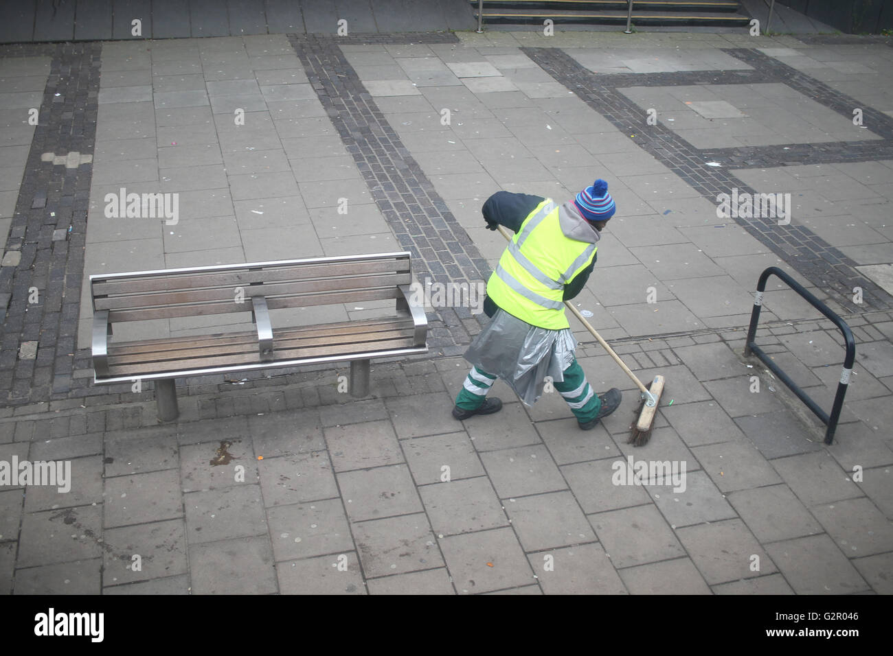 litter picker/council worker/ sweeps street with a broom between a ...