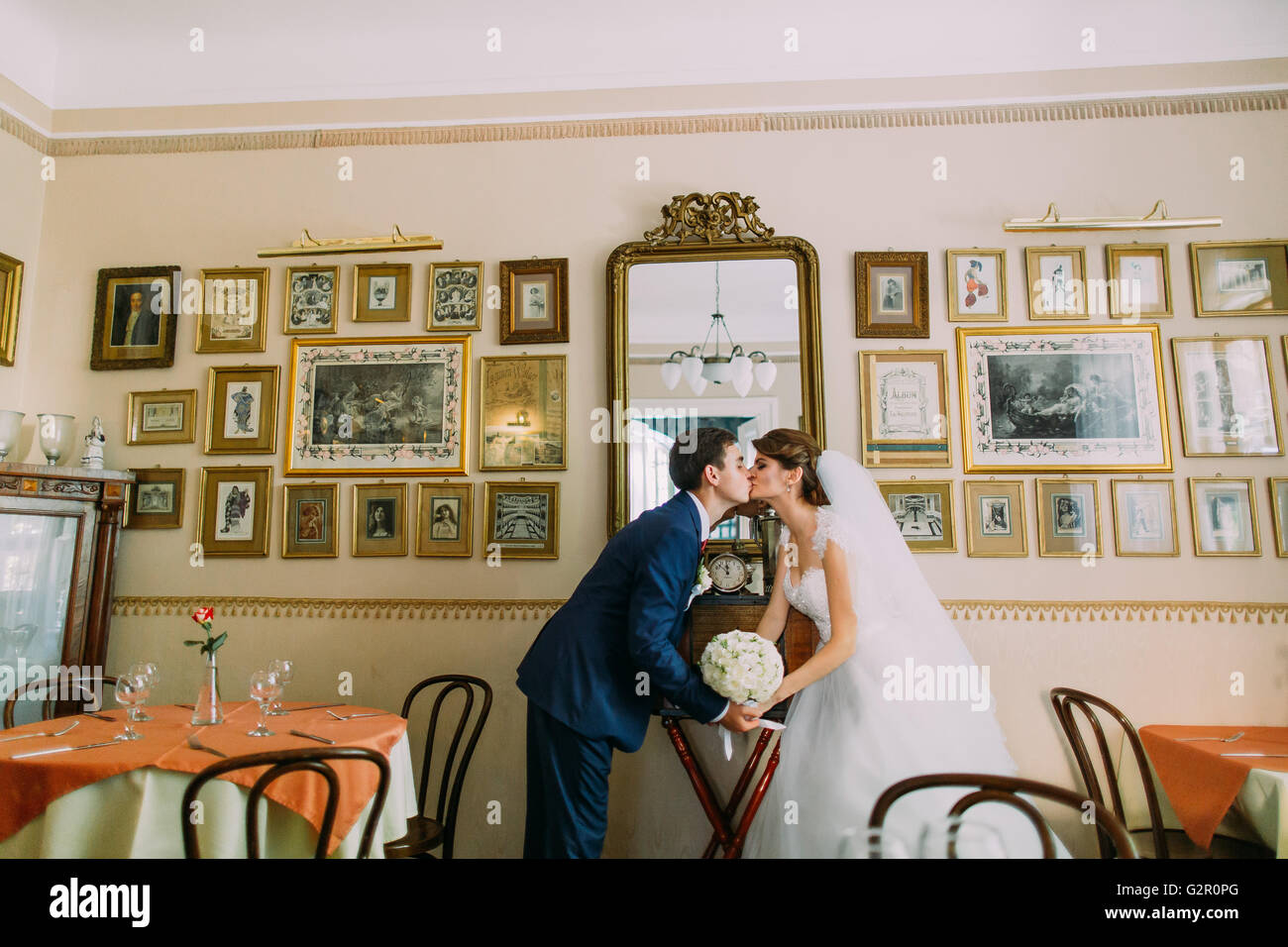 Bride and groom kissing at retro cafe with beautiful vintage interior ...