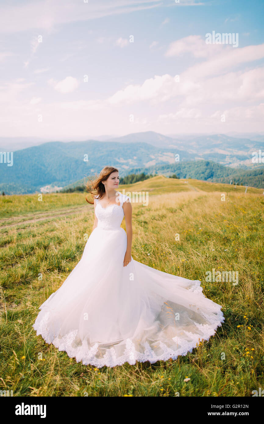 Romantic bride posing on the green and yellow field with small flowers ...