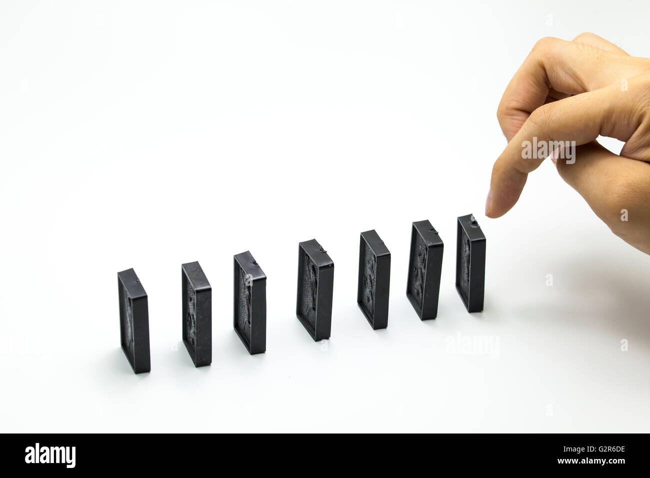 Hand pushing dominoes isolated on white background - domino effect ...