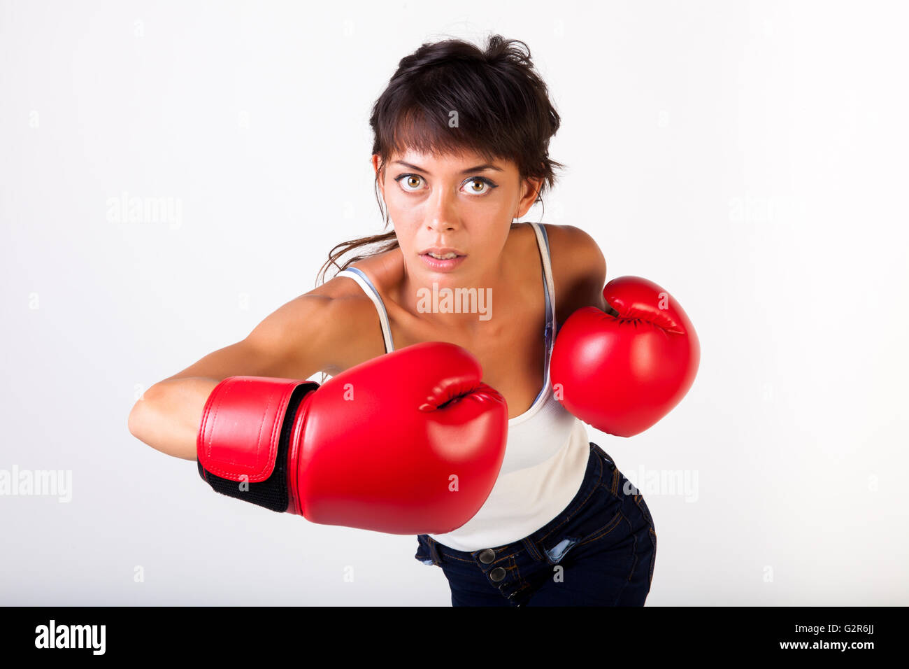 Young beautiful woman punching towards camera wearing boxing gloves on ...