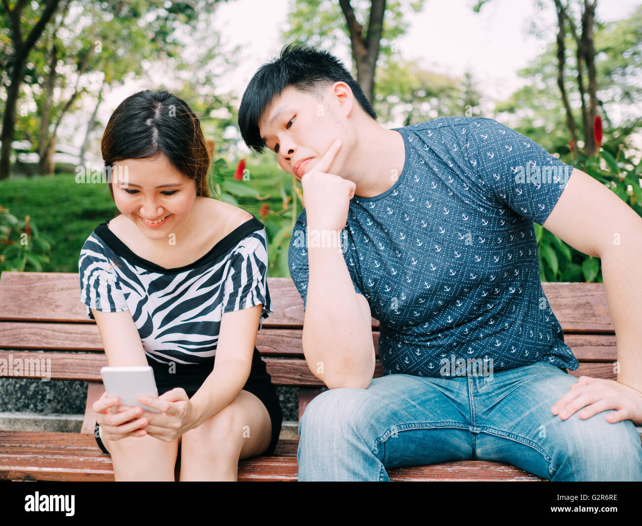 Jealous boyfriend peeking and spying his girlfriend mobile phone while ...