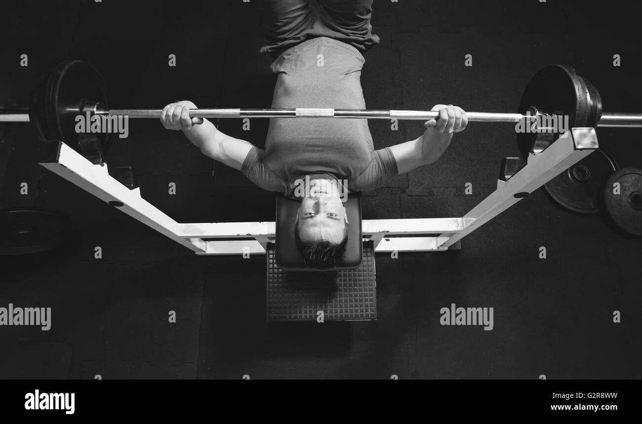 Muscular man lifting a barbell on bench at gym, top view Stock Photo ...