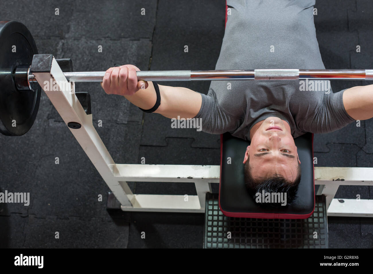 Muscular man lifting a barbell on bench at gym, top view Stock Photo ...