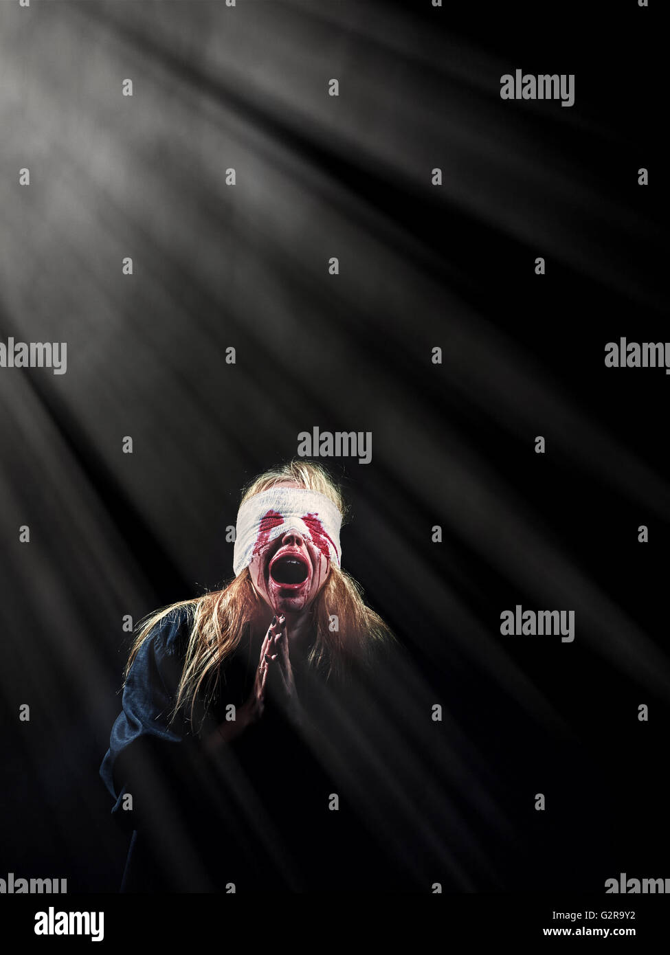 wounded scared bloody girl screaming in light rays on black background ...