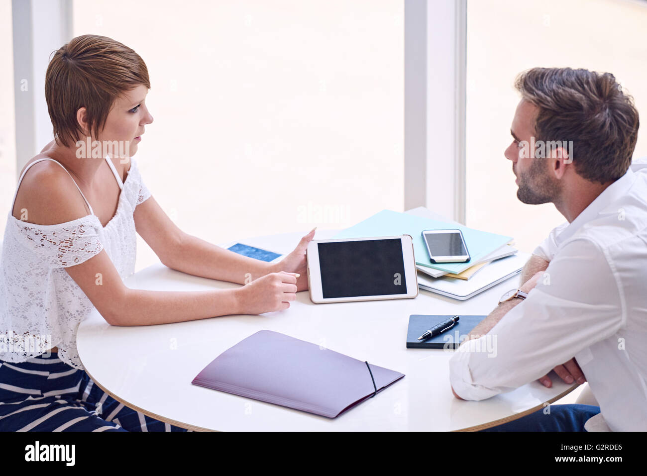 Female creative showing her male partner information on tablet screen ...