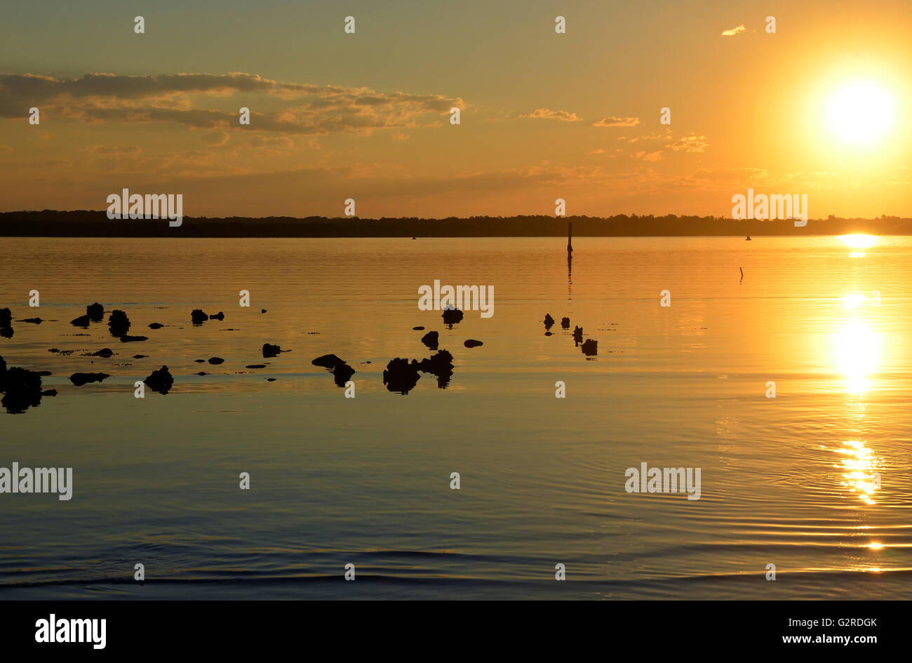 Glowing sun setting (sunset) over Botany Bay with rock silhouettes and ...